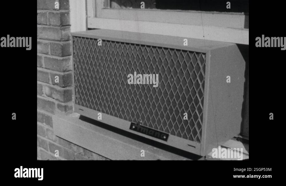 1960s: Window mounted air conditioner. People entering small office ...