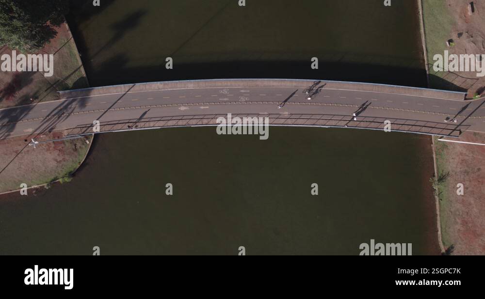 Low Aerial View of People Cycling and Walking on park bridge - Zooming ...