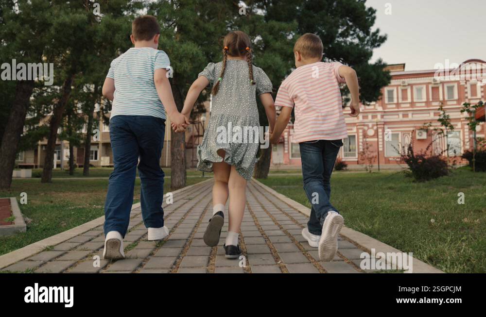 Child Friends run through city park holding hands. Boy girl run along ...
