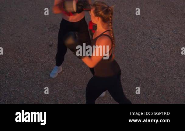 High angle of female fighter practicing defensive boxing on sandy beach ...
