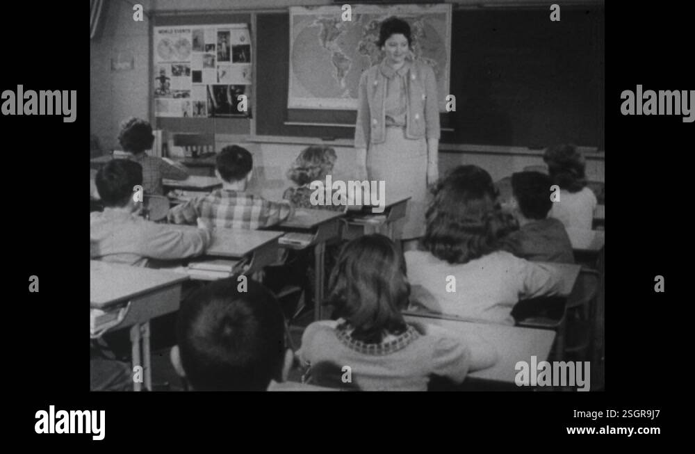 1940s: Classroom. Students wave. Teacher speaks and passes out papers ...