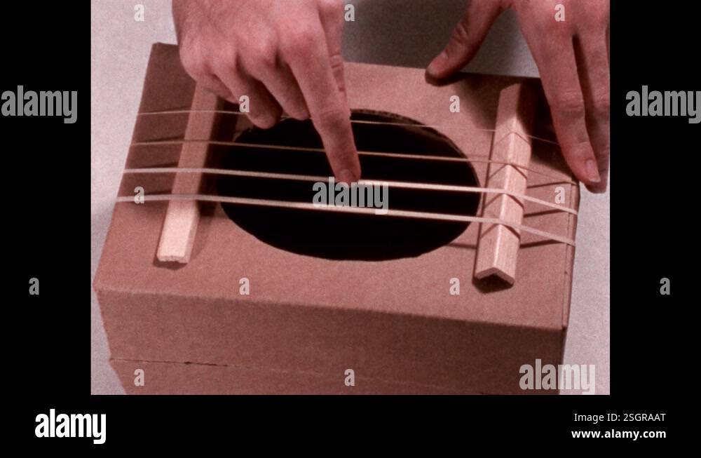 1990s:Fingers pluck strings on homemade music box. Strings vibrate ...