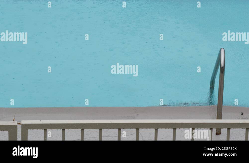Rain drops falling on water of swimming pool, rainy in California motel ...