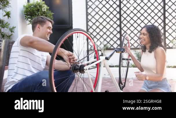 Fixing bicycle wheels, young multiracial couple enjoying outdoor ...