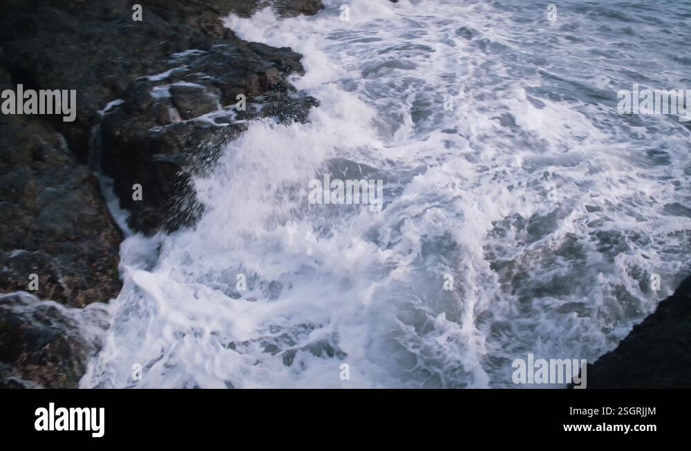 A waves crashes in between two rock formations creating a big splash ...