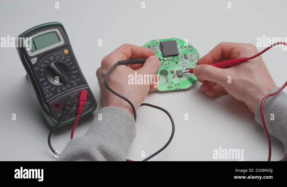 Man diagnosing a faulty circuit board with a multimeter. Medium close ...