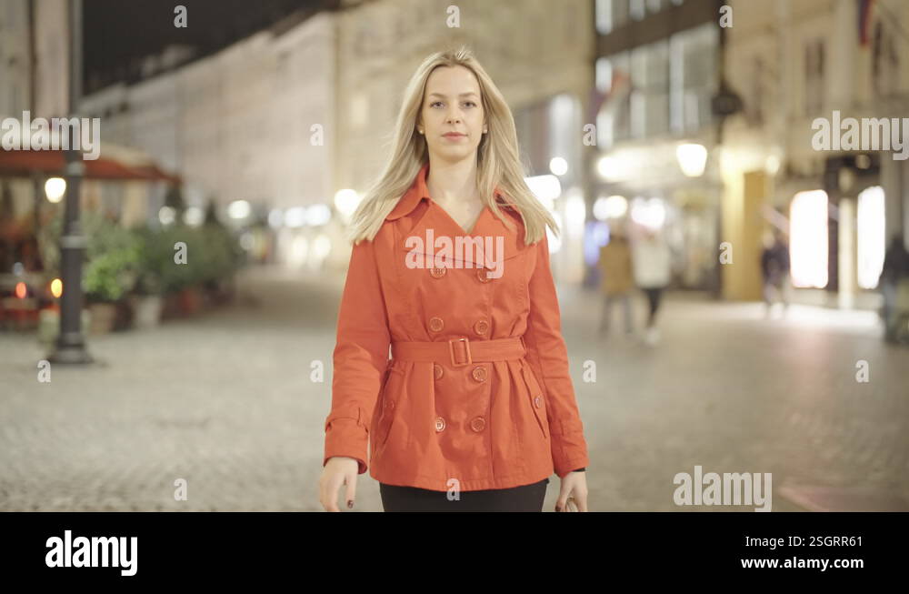 Confident blonde woman in red coat walk through city at night 4K Stock ...