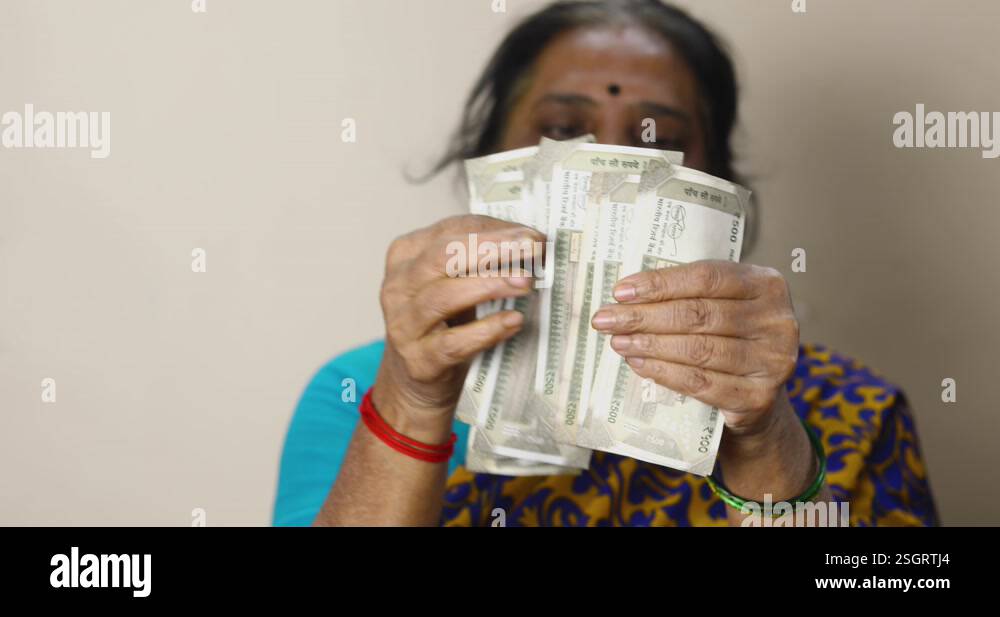 Indian woman counting new Indian 500 rupee notes against white wall at ...