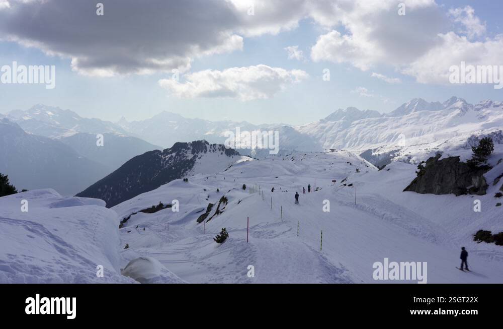 Ski piste in the Aletsch Arena ski resort with happy skiers riding down ...