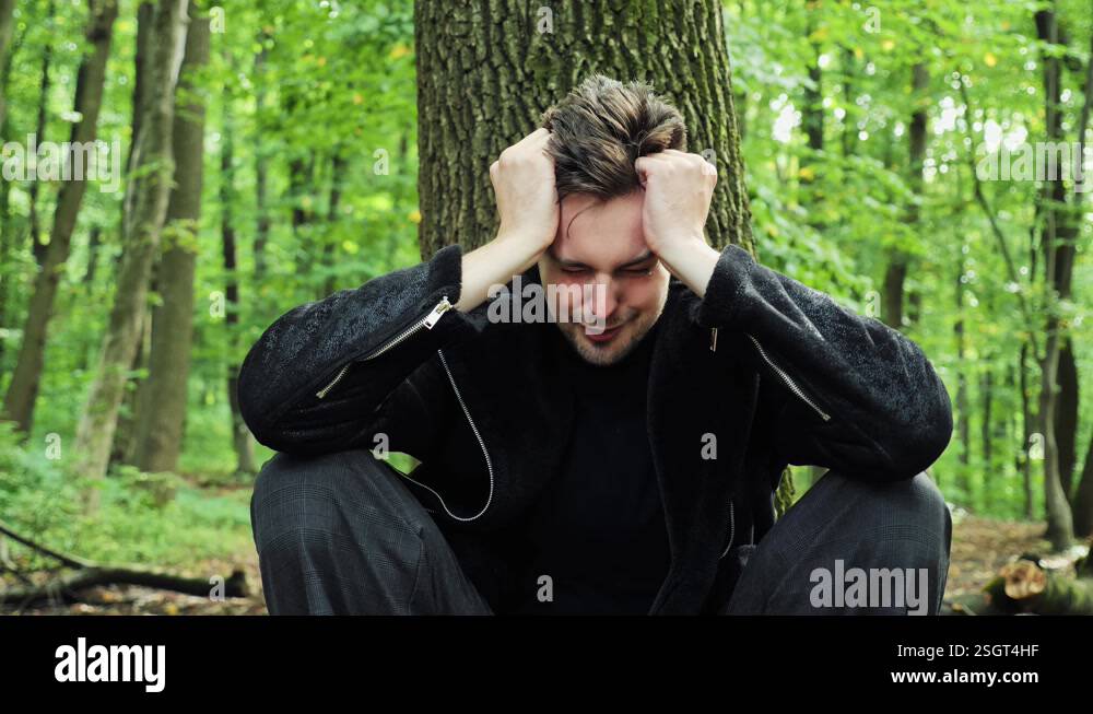 Sad stressed man sitting under tree in the wood feel deep depression ...