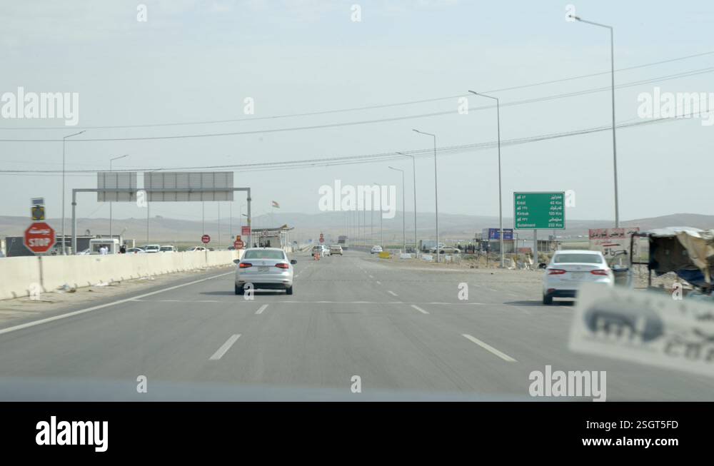 Driving up to a checkpoint on a highway in Iraq with a sign for Erbil ...