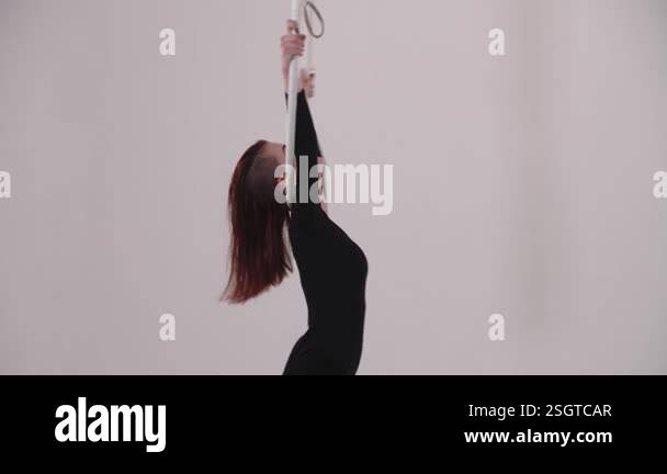 Young woman gymnast hanging on the hoop on her neck under the ceiling ...