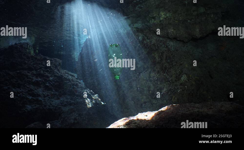 green plastic bottle in cave underwater ocean pollution with sun beams ...