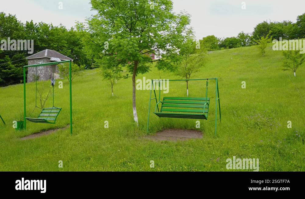 Minimal scene of swing in a green hill field in a cloudy day in spring ...