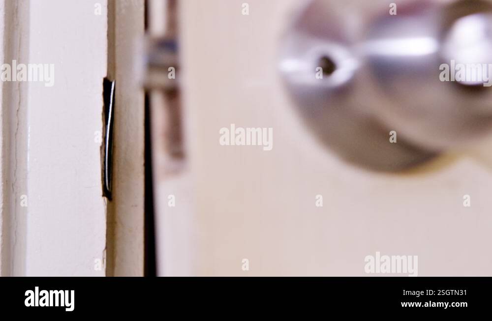 A man unlocking a stainless door knob with his thumb and turning it ...