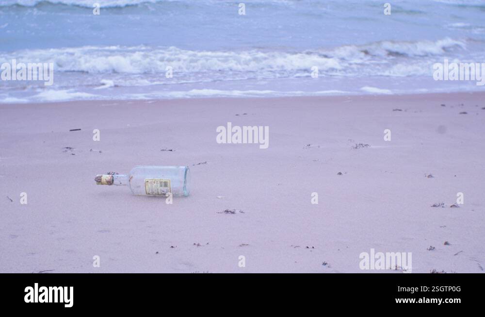 Empty glass bottle on the beach, trash and waste litter on an empty and ...