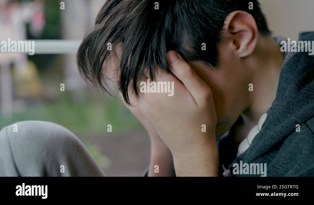 Scared boy refugee crying on window, rubs his eyes at curfew because ...