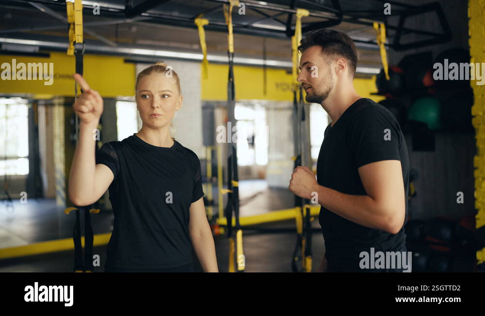 Female gym instructor explaining how to do exercises to male gym goer ...