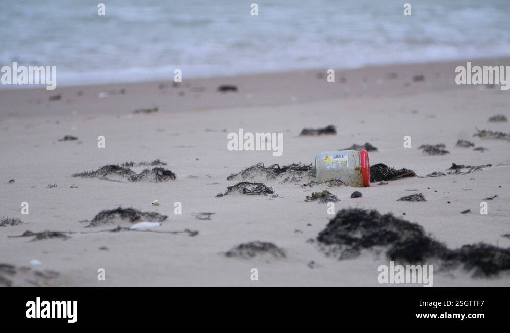 Glass jar on the beach with seaweed, trash and waste litter on an empty ...