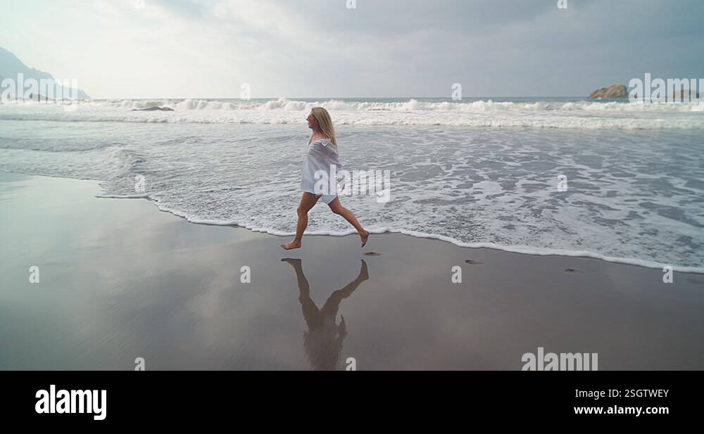 Pretty woman walks at seaside. Slim female walking along sea water ...