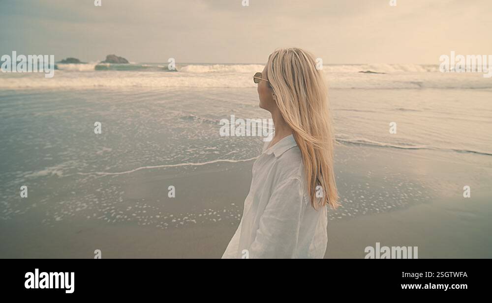 Pretty woman walks at seaside. Slim female walking along sea water ...