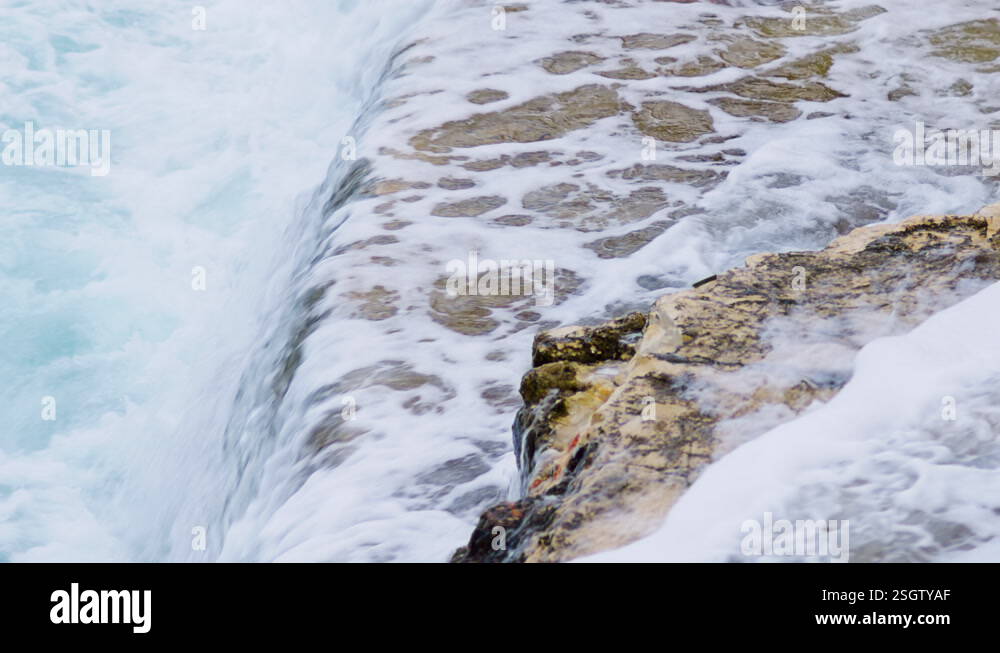 Sea waves crushing on rocky shore, water pour over rocks - close up ...