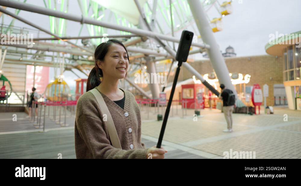 Woman use 360 degree camera to take video at amusement park Stock Video ...