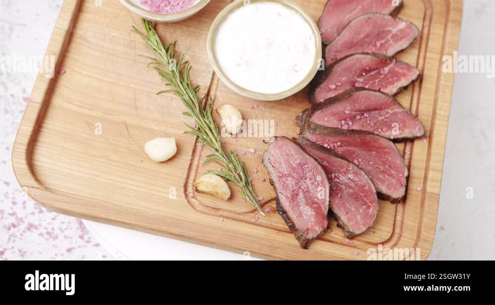 Grilled rare medium beef meat with garlic and rosemary in a Woden white ...