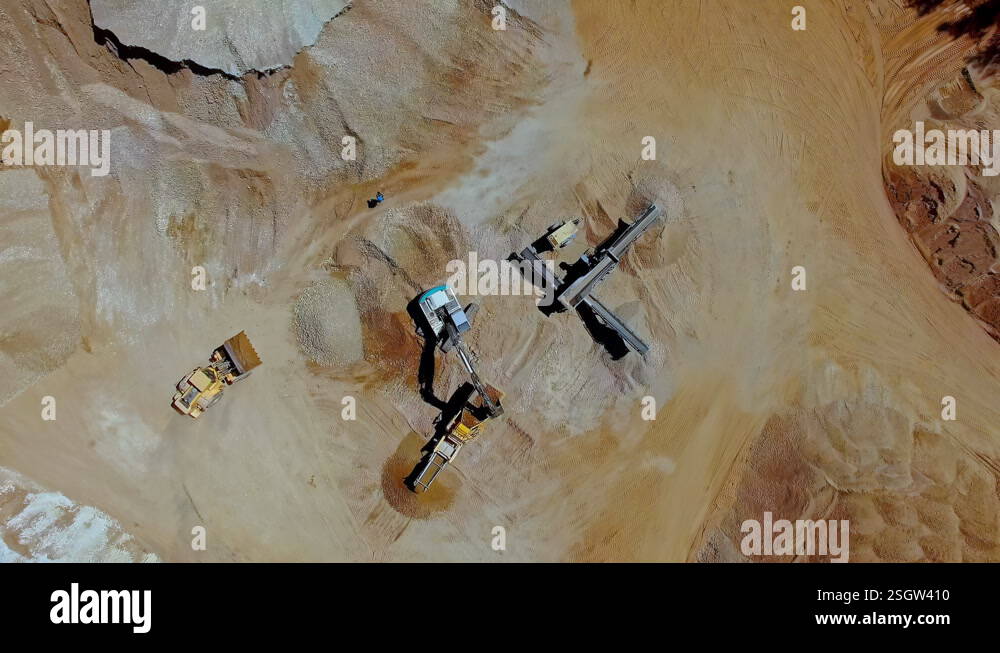 Aerial top-down shot JCB excavator unloading crushed stone inside sand ...