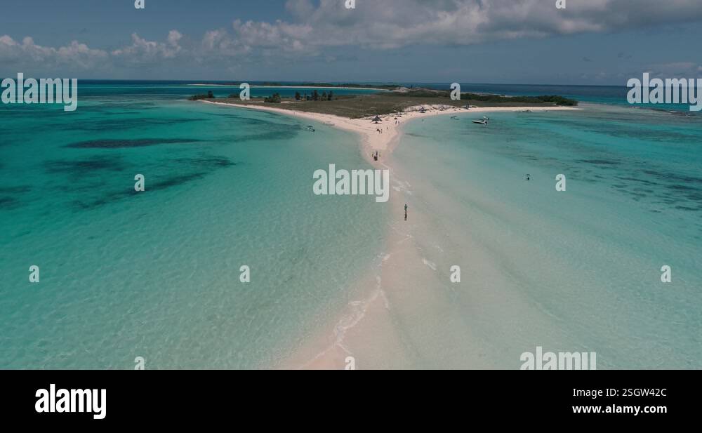 Tourist walk on flooded sandbank with island and palm trees in ...