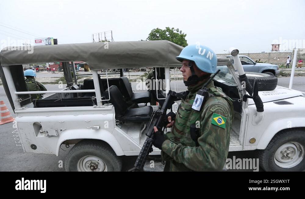 Armed Soldiers stand guard around a white UN Landrover parked on an ...