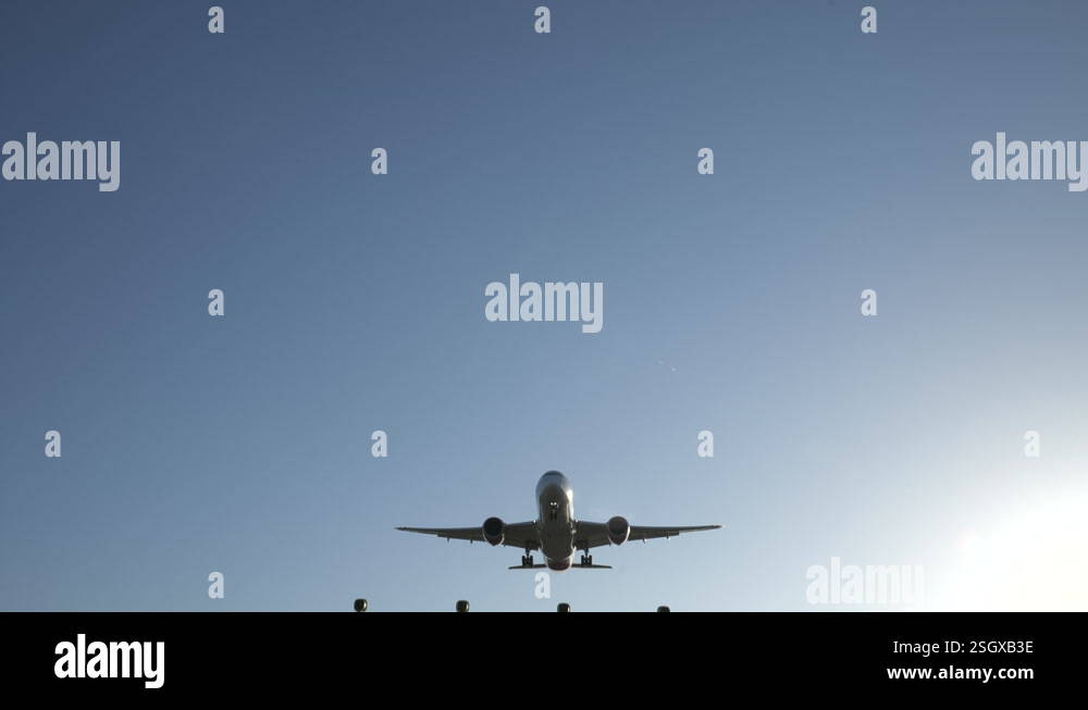 Slow motion commercial passenger jet flies overhead on final approach ...