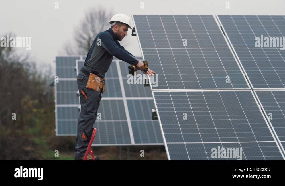 A professional man in a special uniform installs a solar panel at a ...