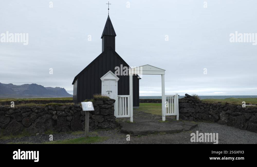 Backwards handheld shot of an old wooden black church with a white door ...