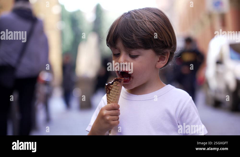 Young boy eating ice cream cone outside. Child eats italian gelato ...