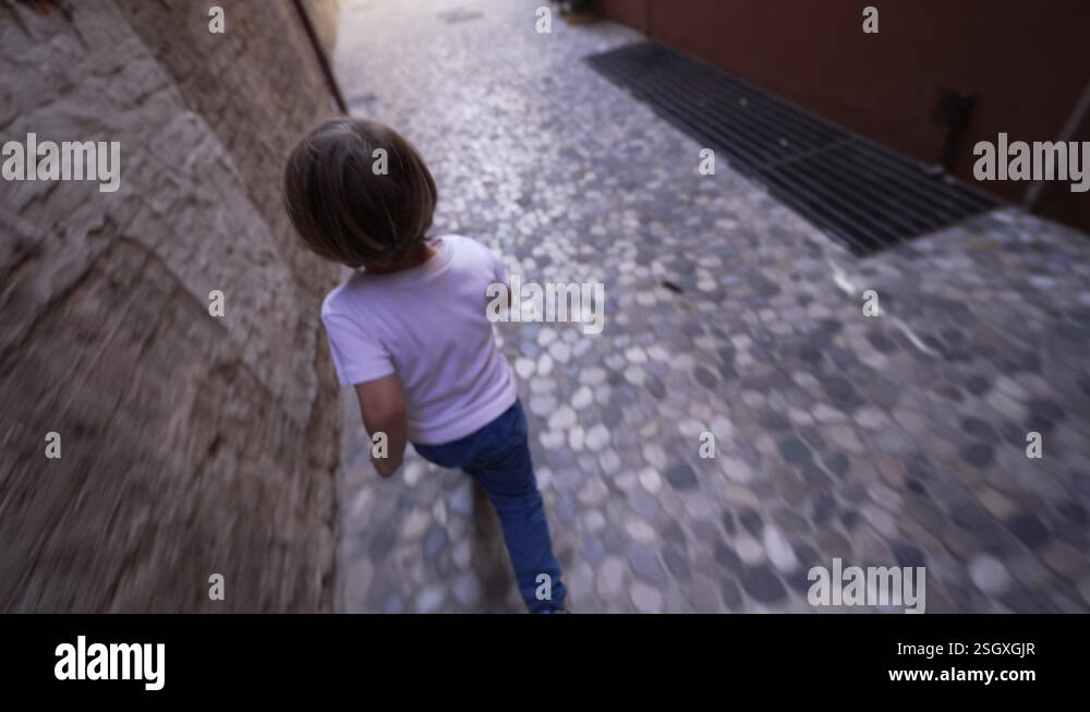 One happy small boy running on cobblestone European street in Italian ...