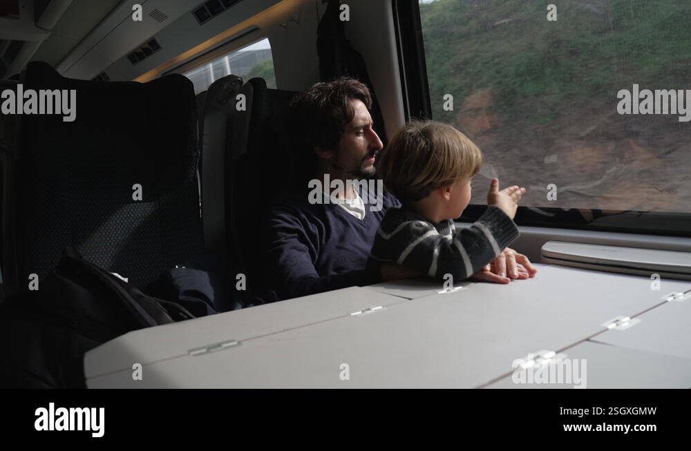 Father and son traveling by train together. Passengers seated by high ...