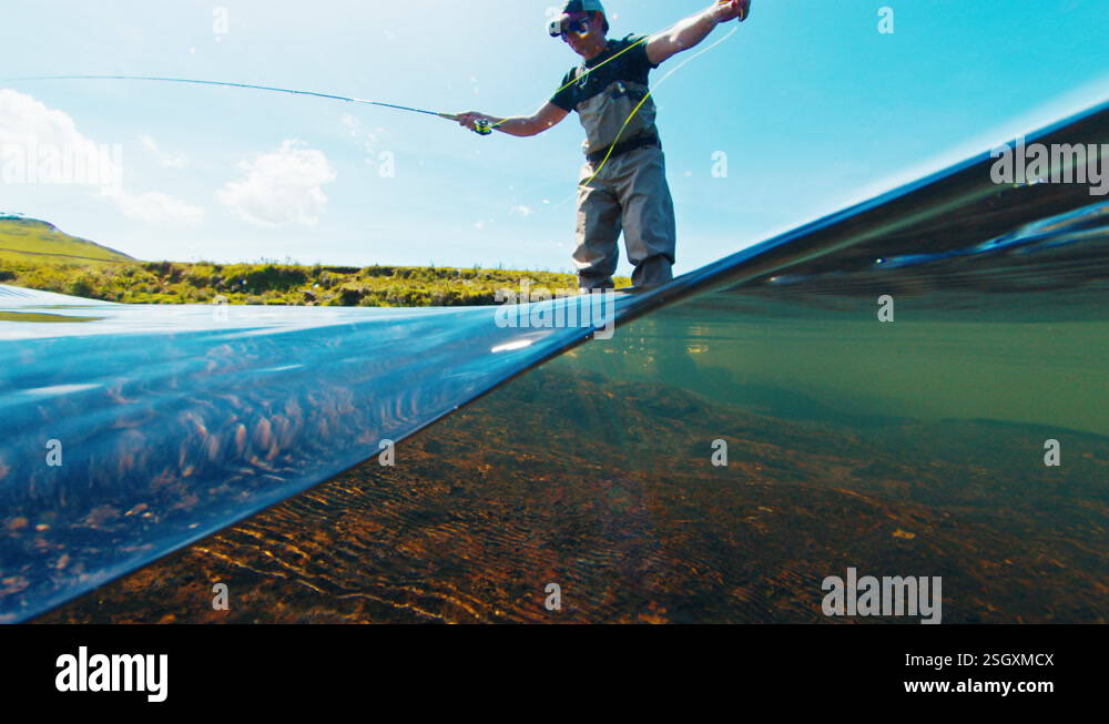 Man fly fishing on the river. Angler stands in the river in waders and ...