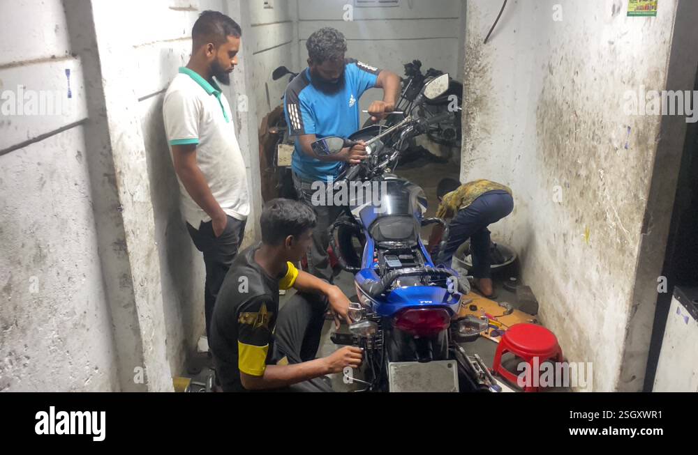 Inside Local Garage With Group Of Mechanics Working On Motorbike In ...