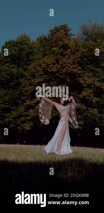 Vertical. Girl belly dancing in the forest. Oriental dance. Woman in ...