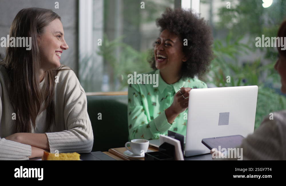 Young diverse group of friends laughing and smiling seated at coffee ...