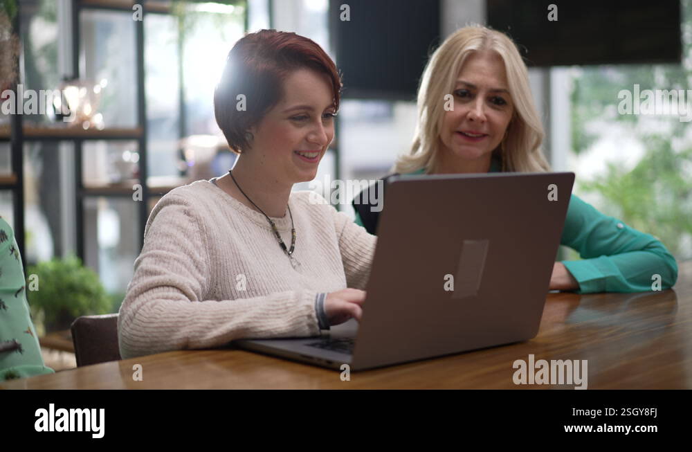 Female senior executive coaching younger staff in front of laptop ...