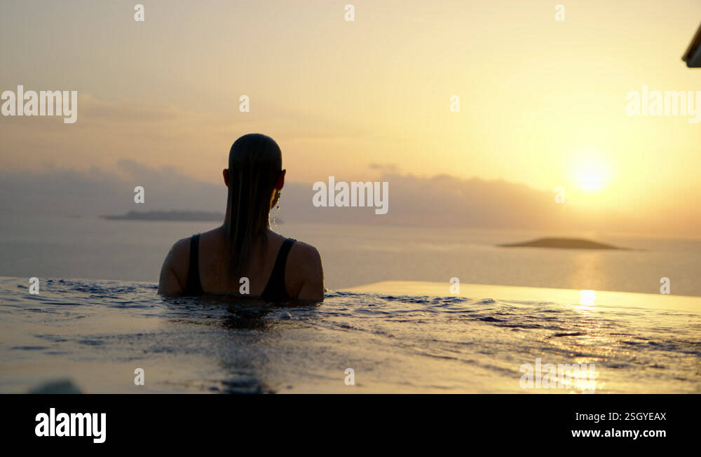 slender unrecognizable young woman emerges from infinity pool with ...
