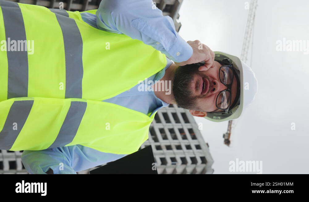 Vertical Screen: Civil engineer talking on phone at construction site ...