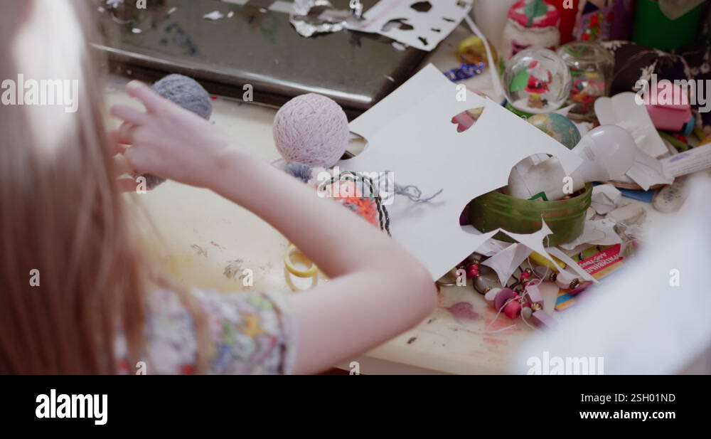 child threading threads from yarn skein around cardboard circle Stock ...