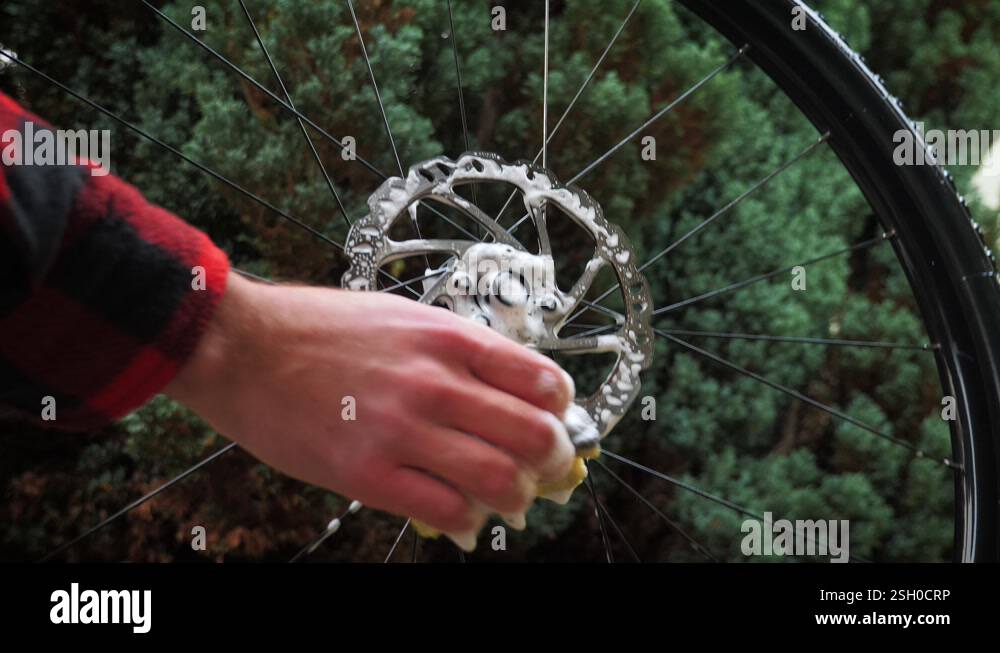 Bike mechanic cleaning bicycle wheel with soap. Man washing wheel of ...