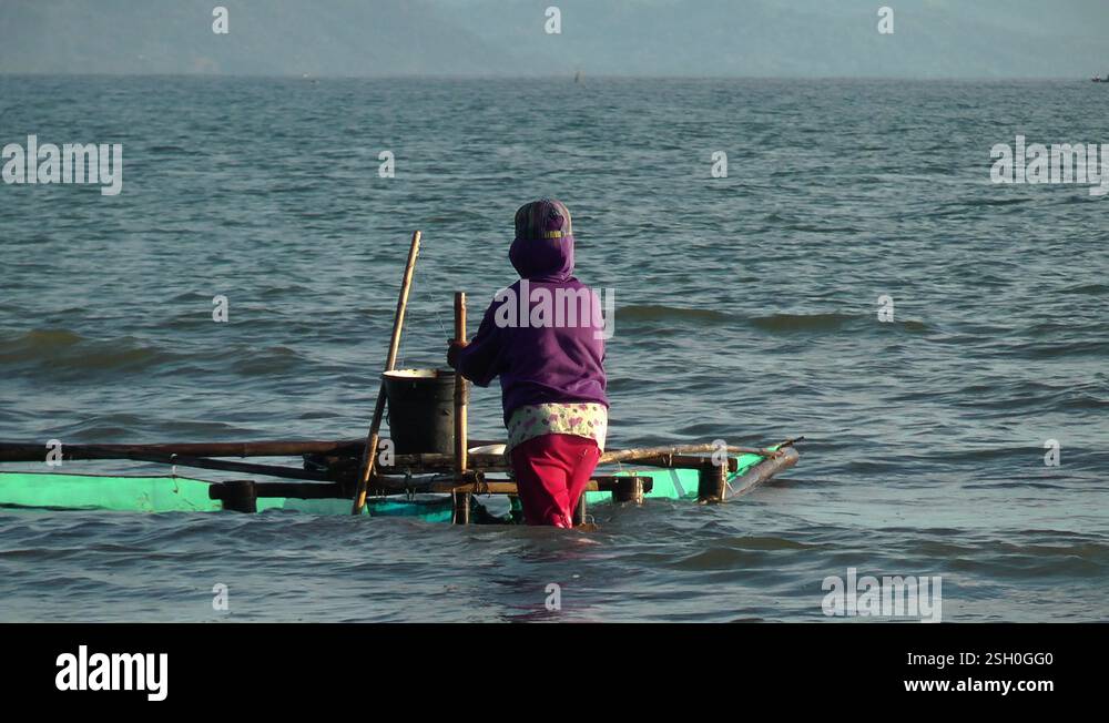 Filipino woman catching Milkfish fry in shallow water in Philippines ...