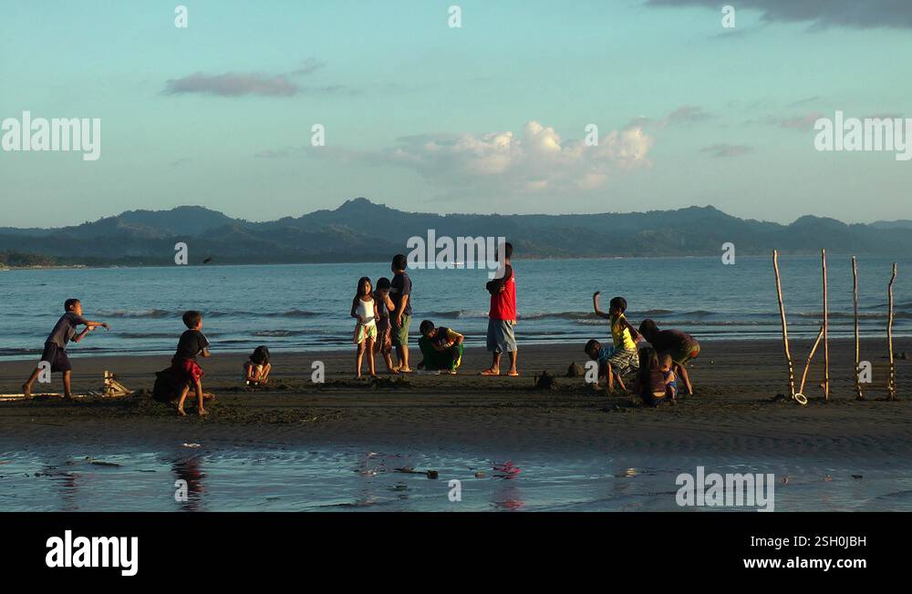 Children playing on Datu Sumakwel Beach during a vivid sunset in ...