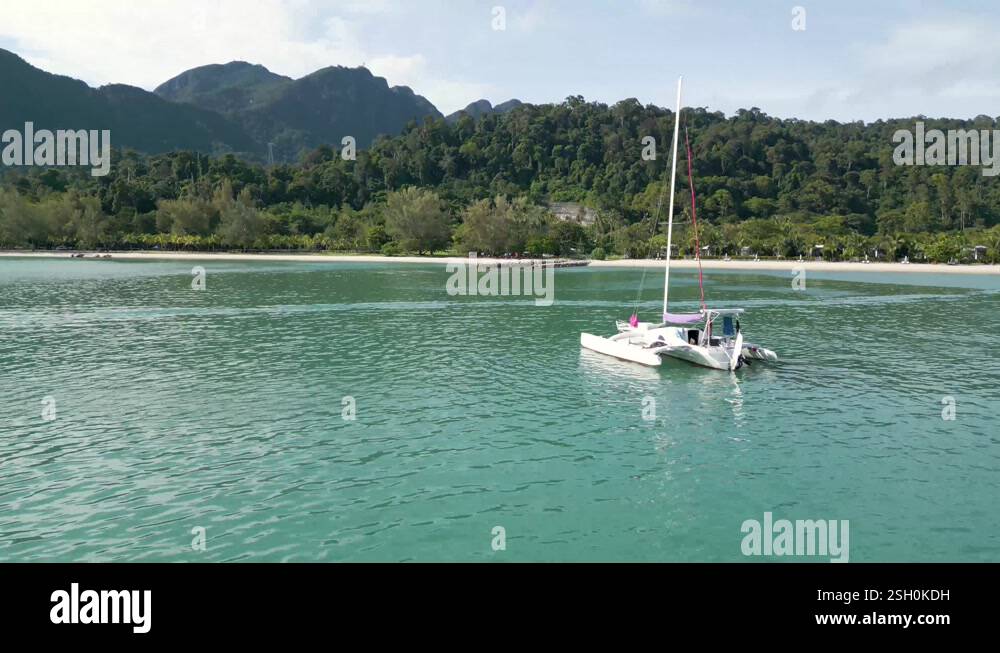 A yacht arriving at Pantai Kok Beach, Langkawi, island with jungle and ...