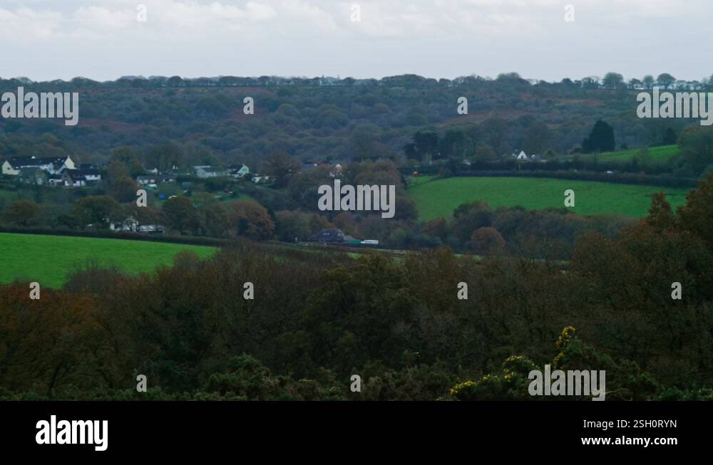 Slow panning shot of a village nestled in amongst fields and trees in ...